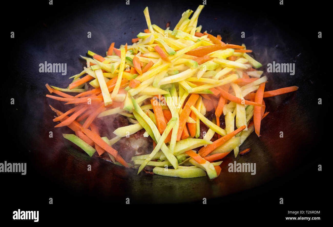 Uzbek rice pilaf cooking process. Yellow and orange carrot in cauldron ...