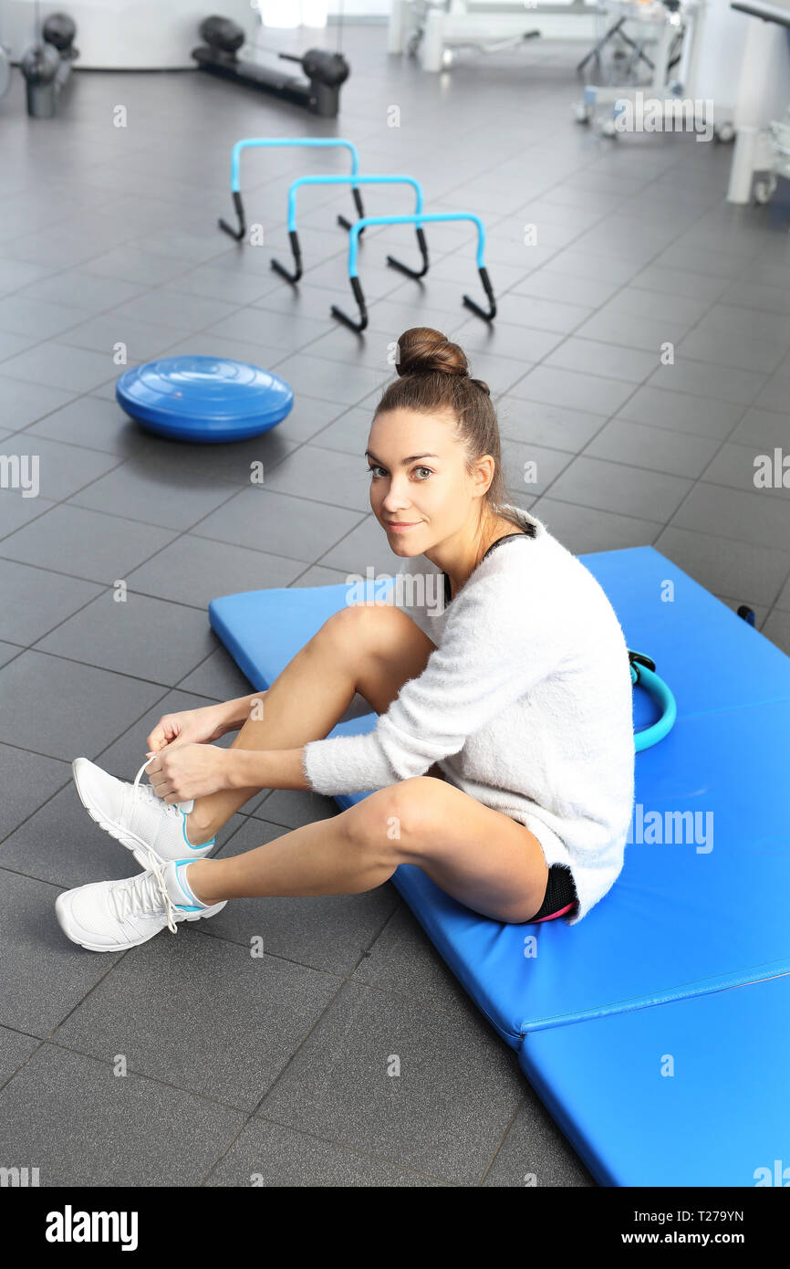 A young, attractive woman in an exercise room on a blue sports mattress ...