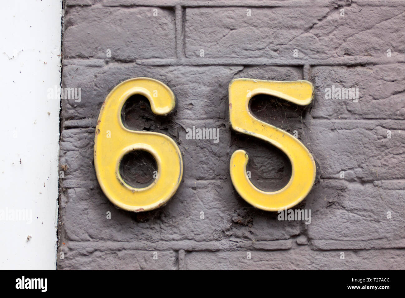 Yellow house number 65 of baked stone Stock Photo - Alamy