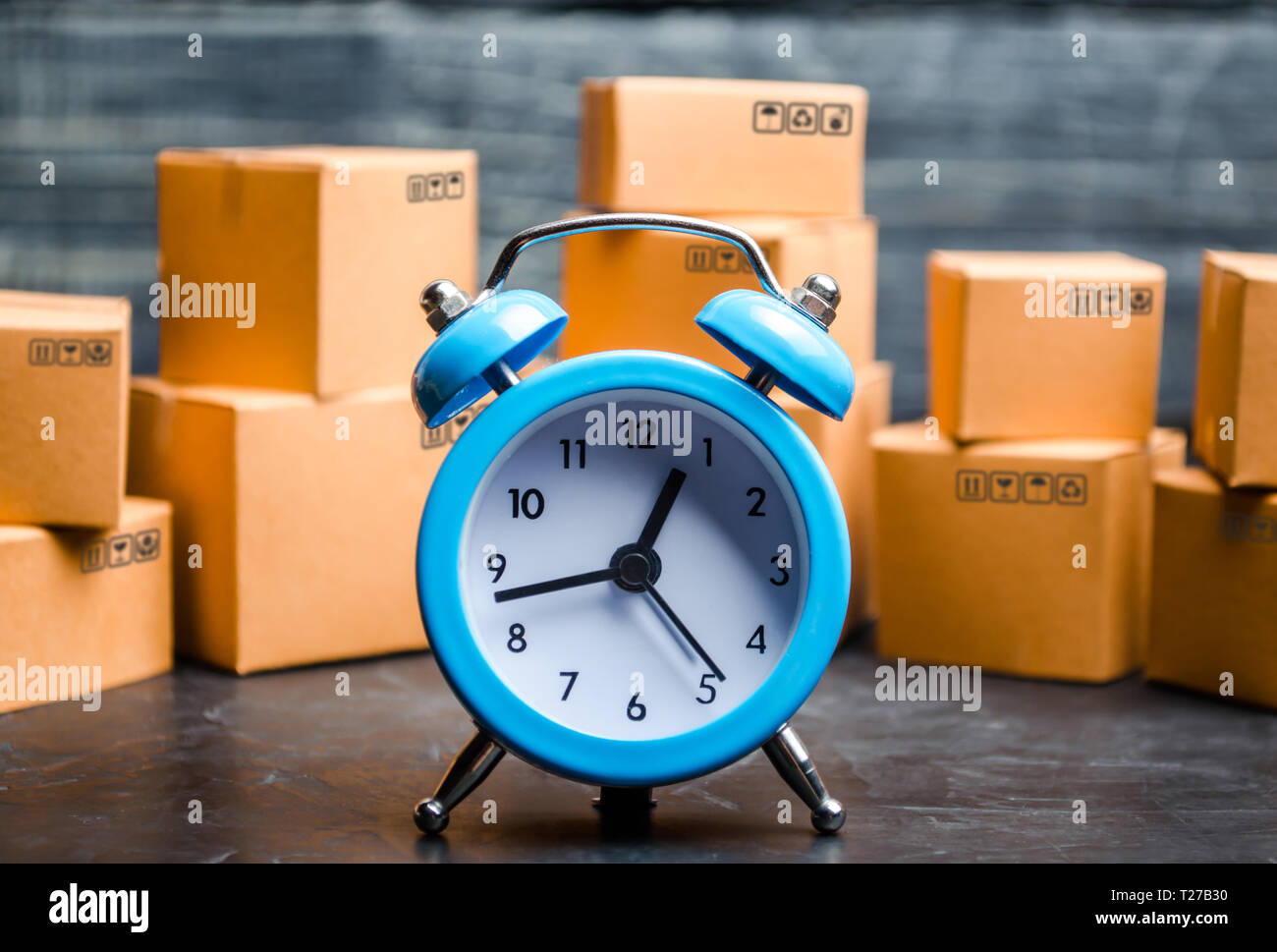Cardboard boxes and a blue alarm clock. Time of delivery. Limited ...