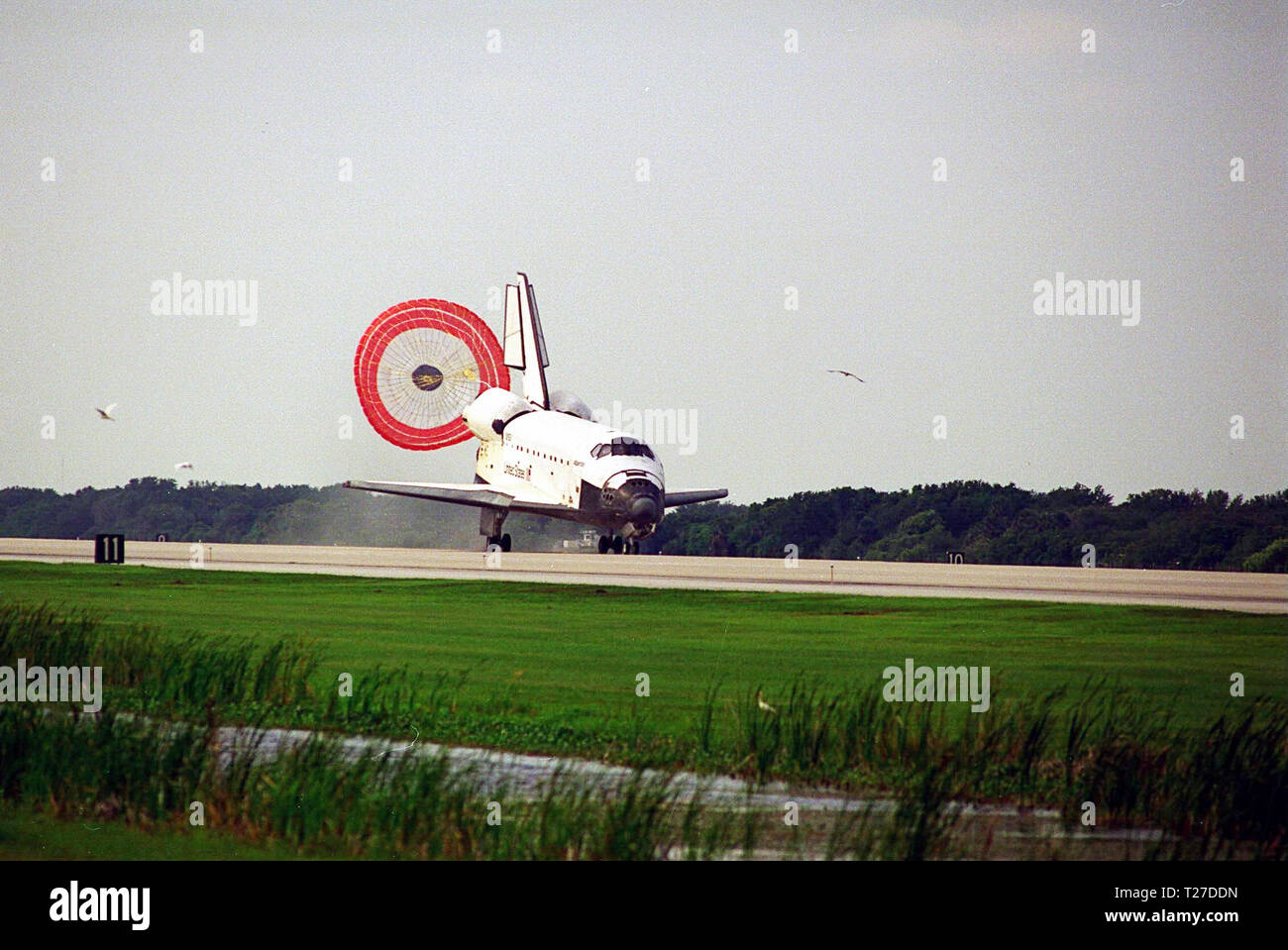 The orbiter drag chute deploys after Atlantis touches down on Runway 33 ...