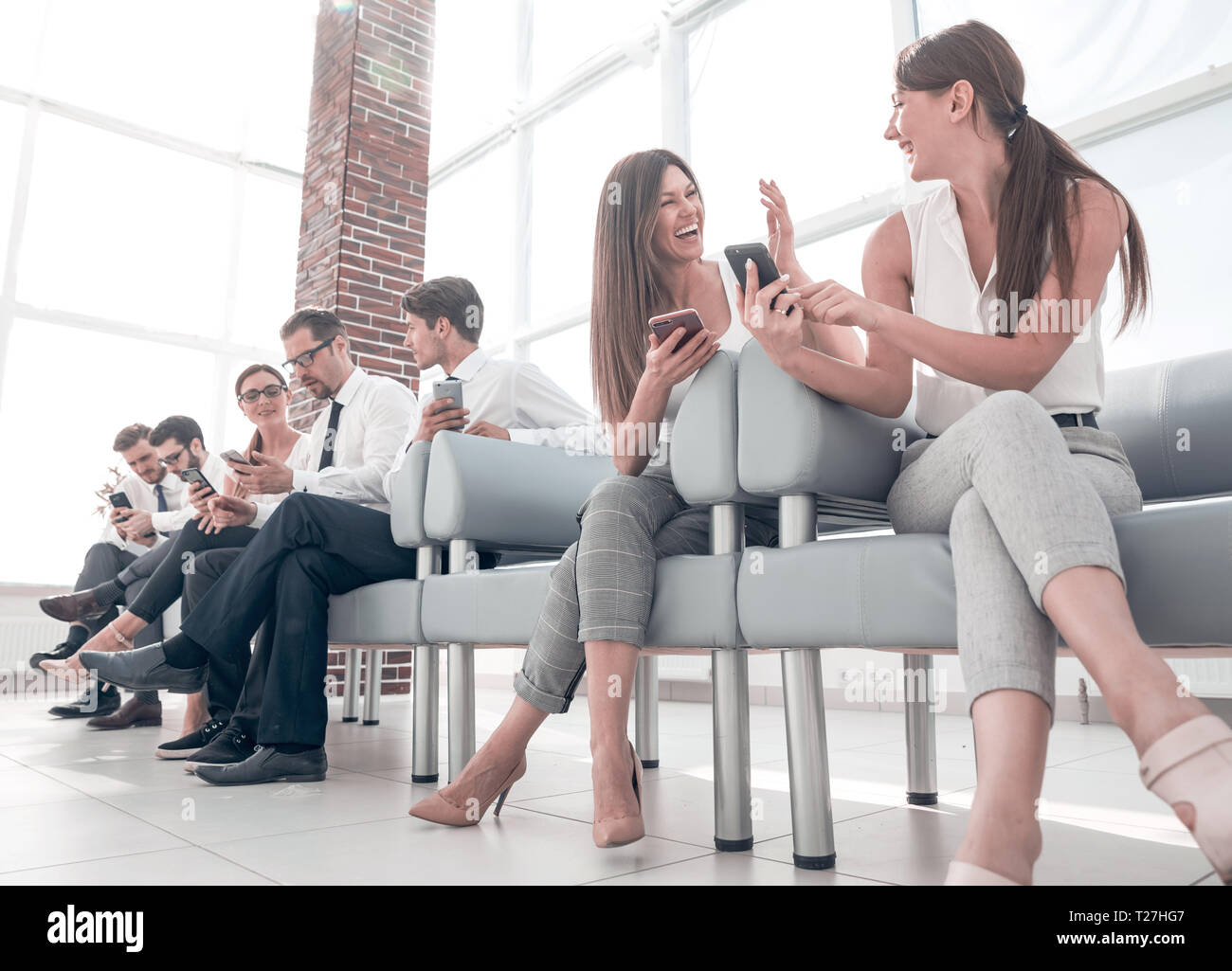 group of employees with mobile phones sitting in the office lobby Stock ...