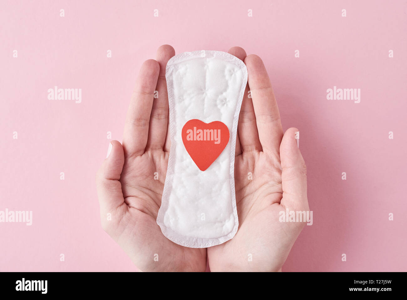 Woman hands hold sanitary pad with red heart on pink background Stock ...