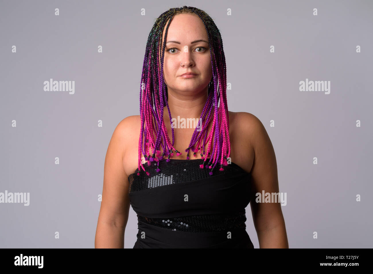 Portrait of rebellious woman with dreadlocks and piercings on face ...