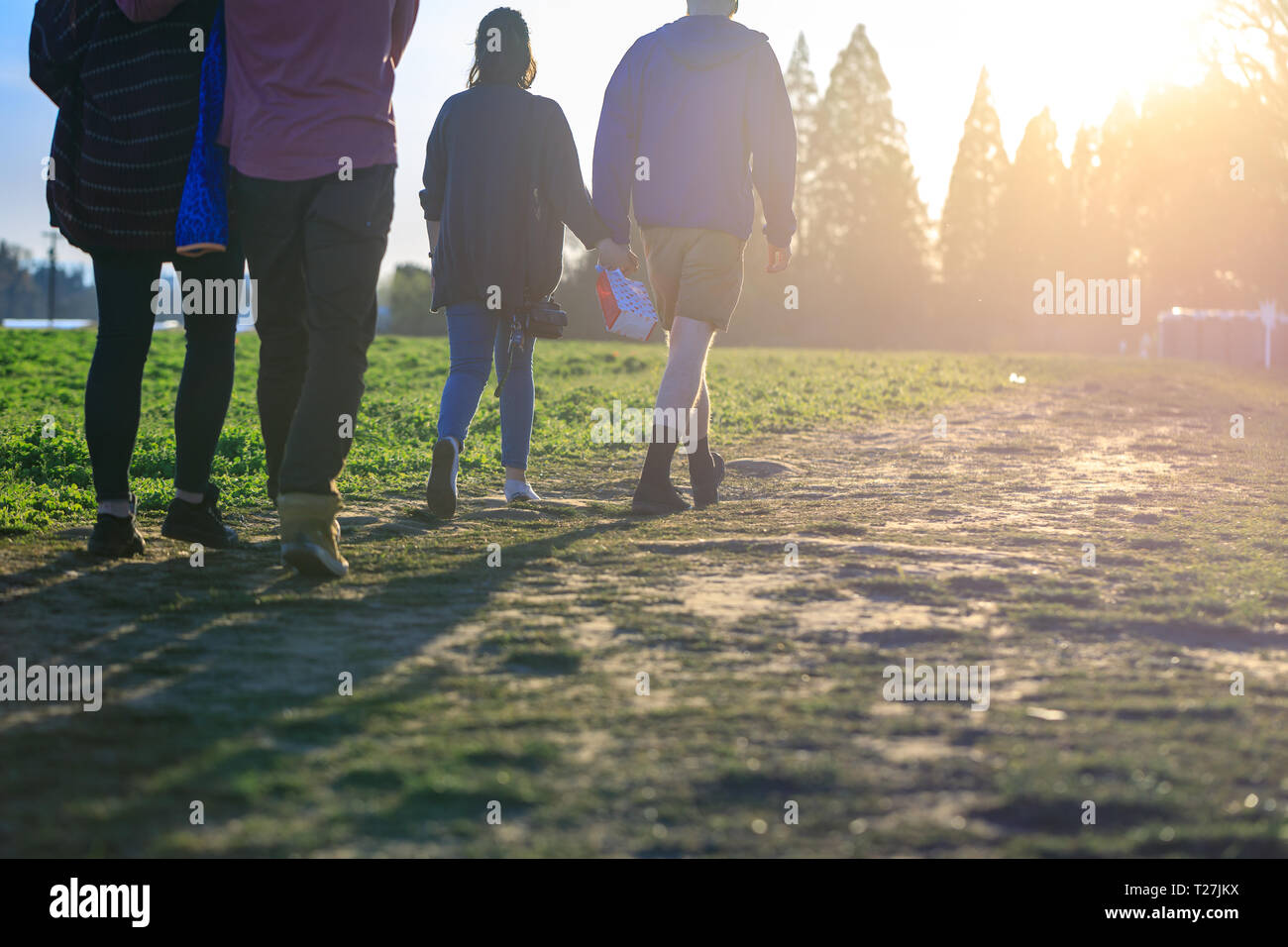 People walking through a park facing the sun, Spring season Stock Photo ...