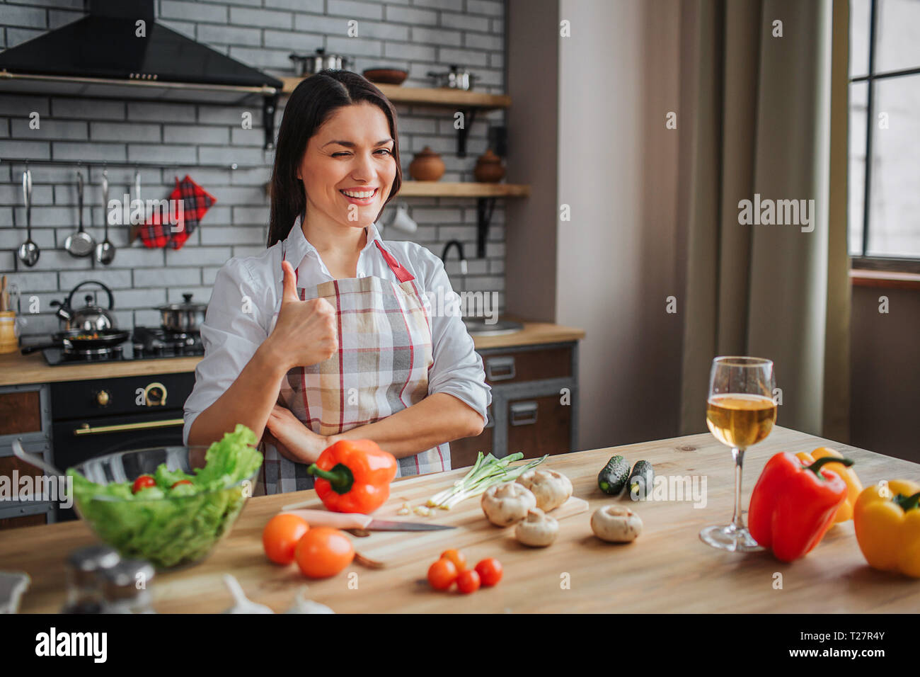 Positive happy woman sit at table in kitchen. She look on camera and ...