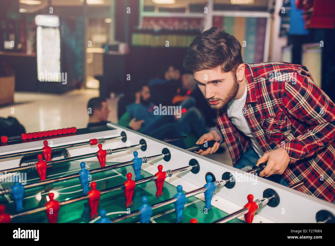 Young man playing alone at table soccer in room. Intense game. Guy ...