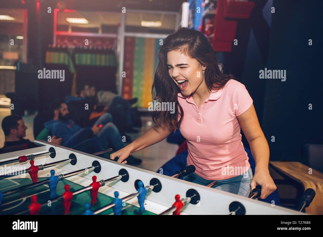 Playful young woman play table soccer in room. She scream. Model ...