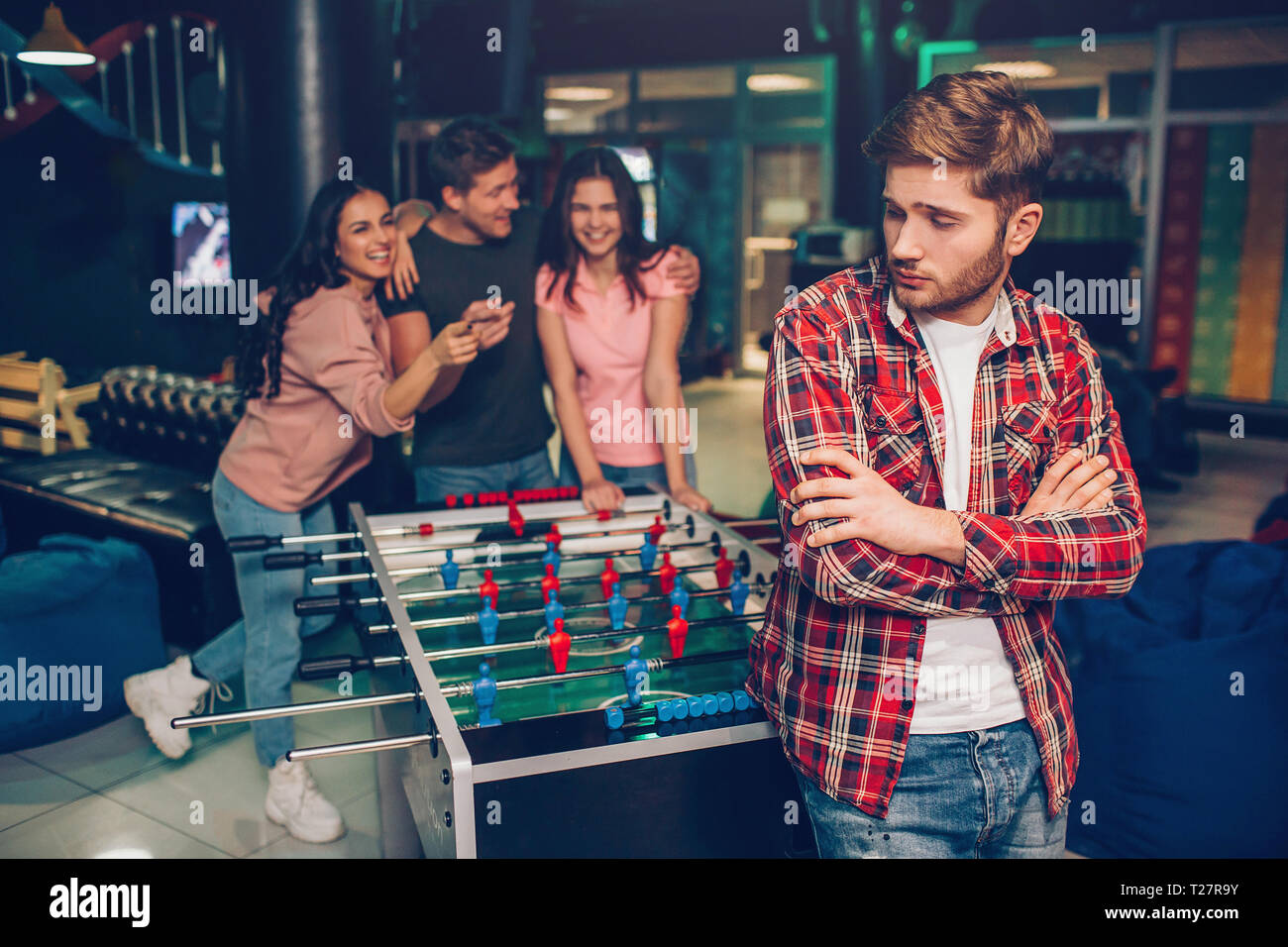 Upset young man stand in front in playing room. He look backwards. His ...