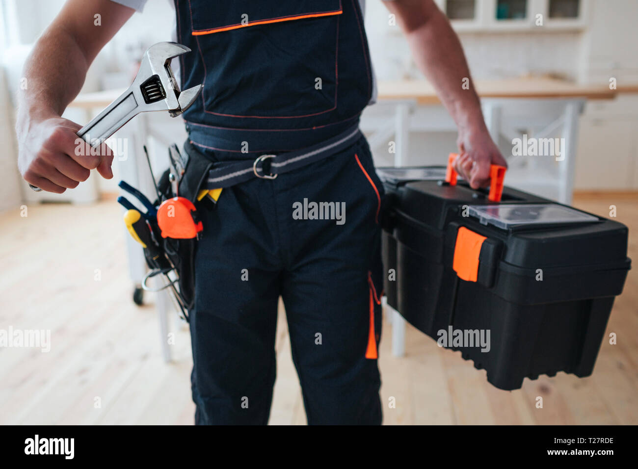 Cut view of handyman holding tool box and wrench in hands. He stand in ...