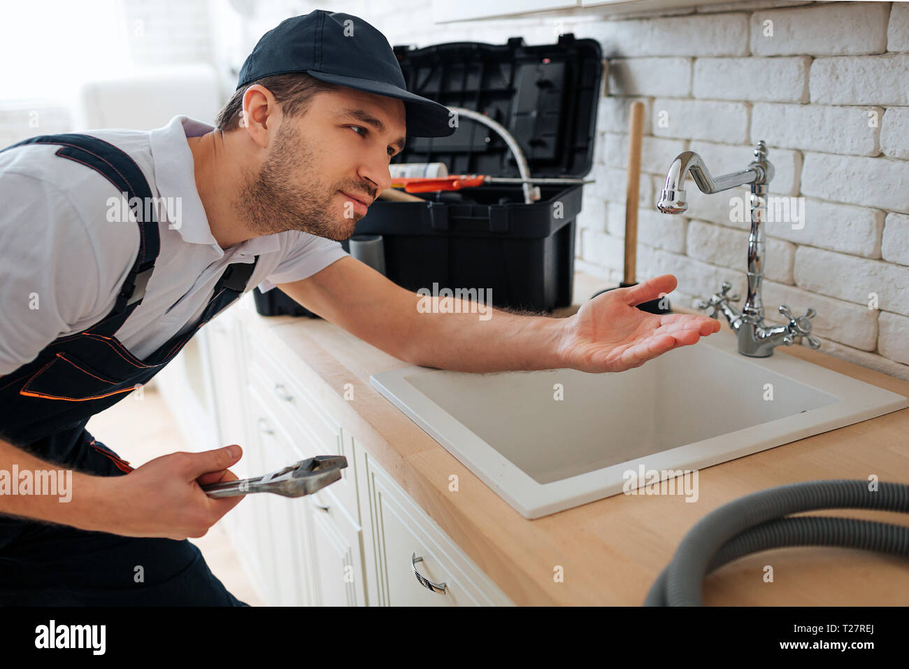 Young handyman check tap for leaking. He hold hand under it. Man stand ...