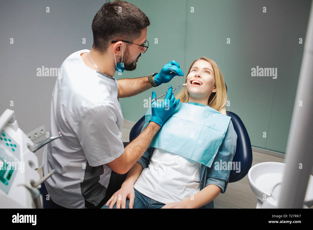 Dentist stand uppon client and using syringe for putting pain killer ...