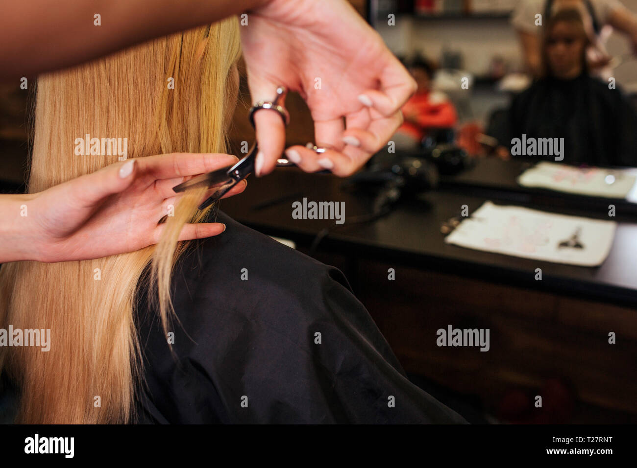 Close up of hairdressers hand cutting blonde hair. Doing new haircut in ...