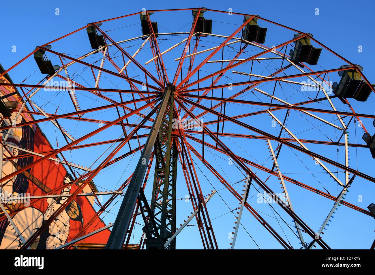 Photo of an antique, red Ferris wheel taken in the daytime looking up ...