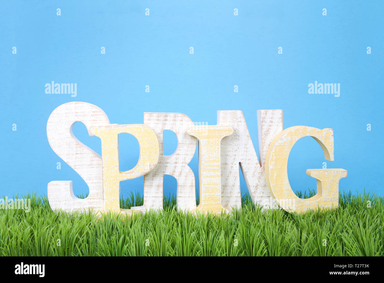 Wooden letters spelling SPRING sitting in green grass with blue ...