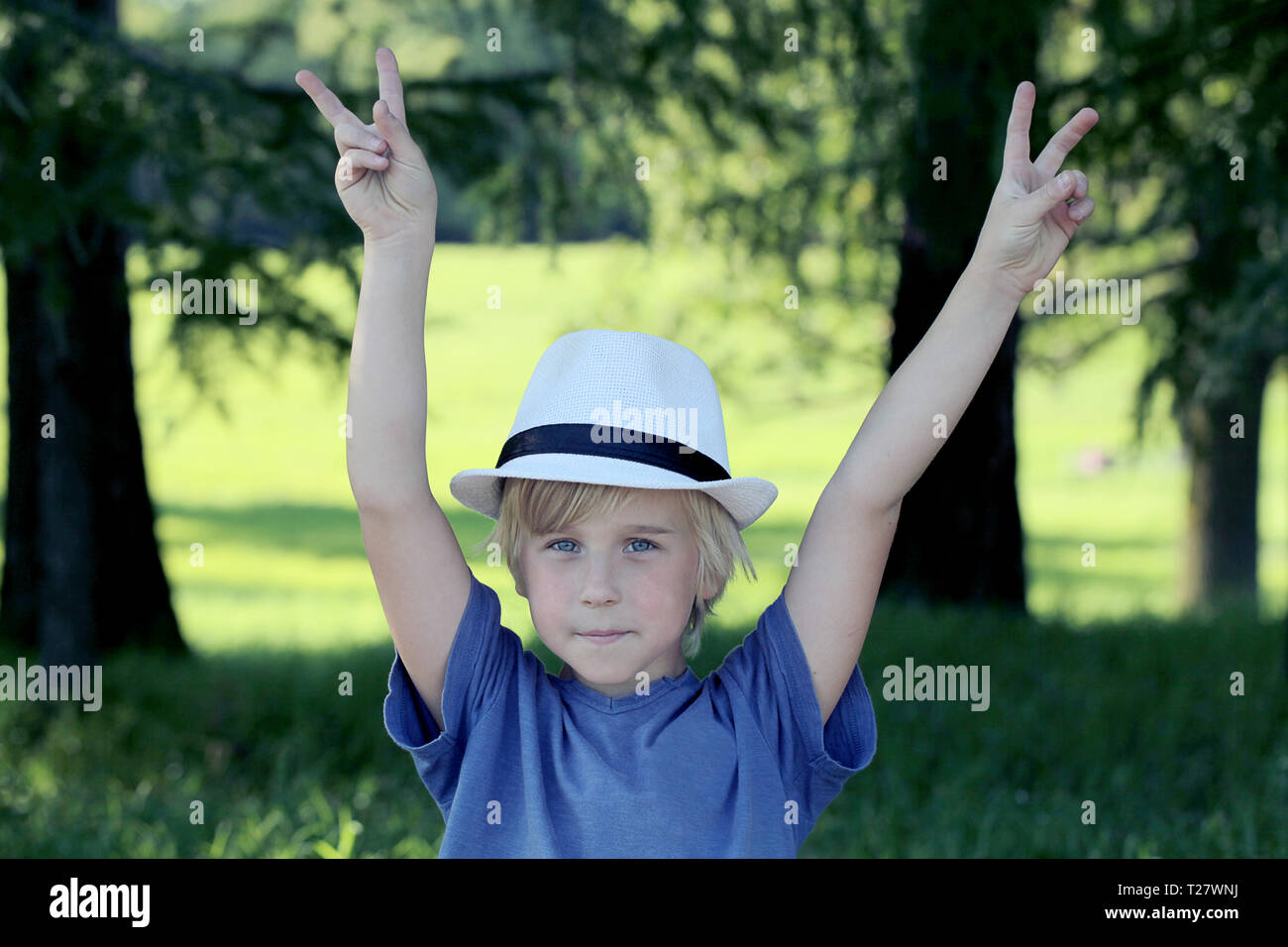 Portrait of boy showing victory hand sign on nature background Stock ...