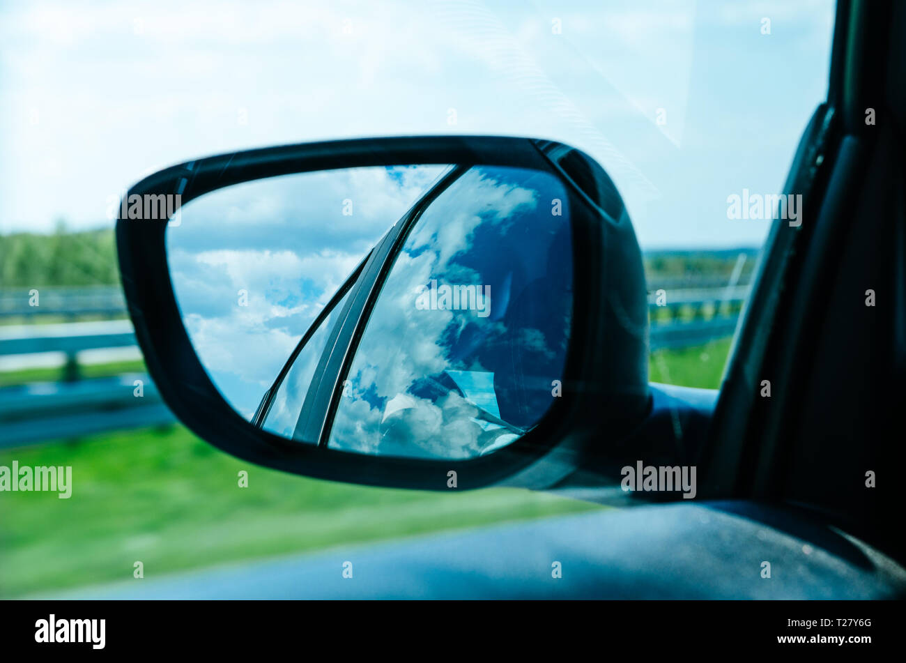 Blue sky with clouds in the sideview mirror of a car, on road ...