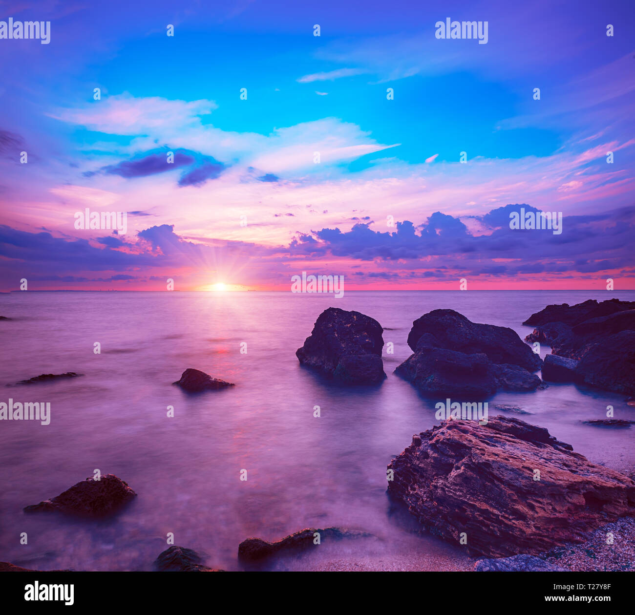 Beautiful colorful sunrise at the sea with dramatic clouds and boulders ...