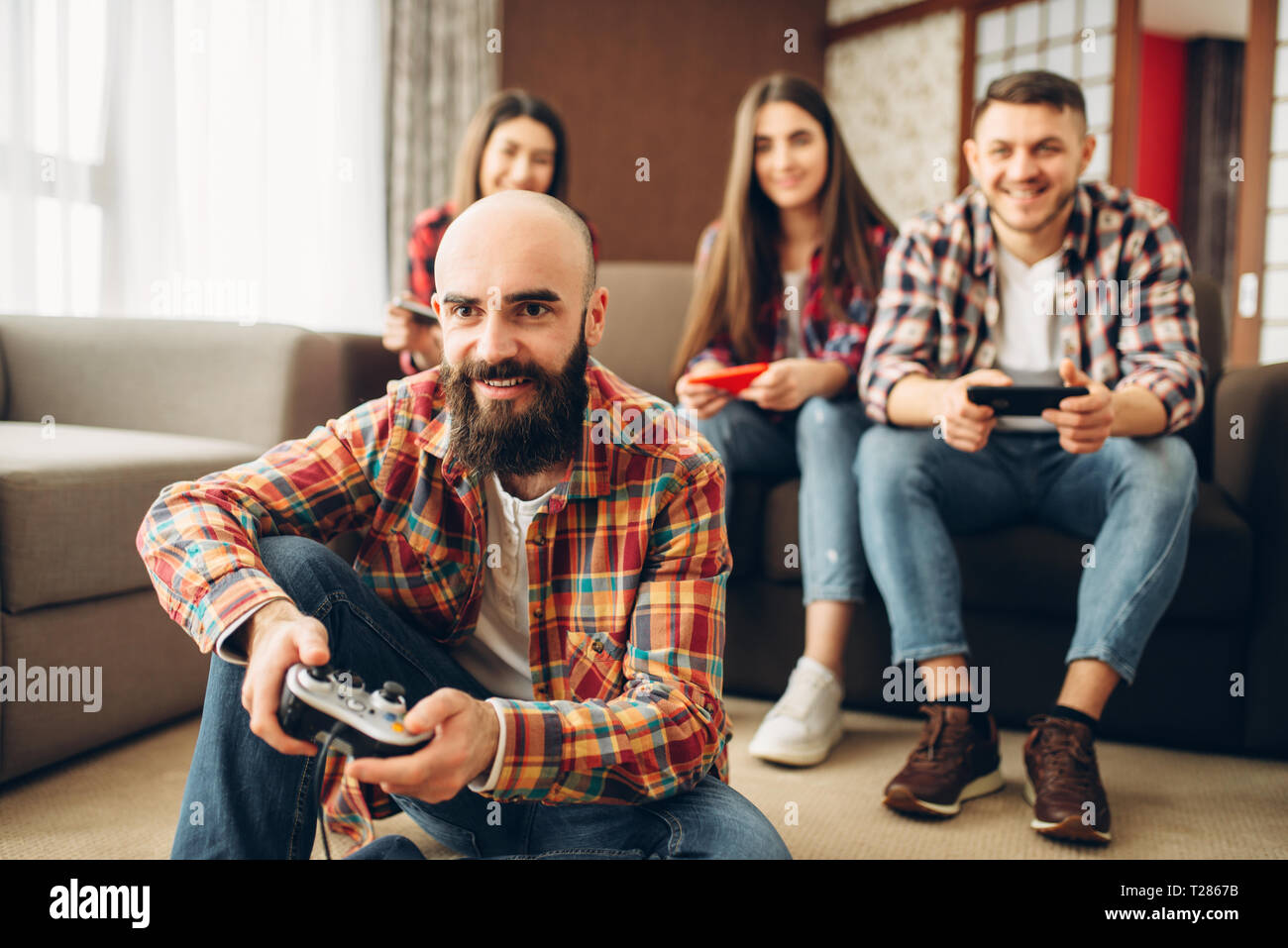 Smiling friends with joysticks plays tv console at home. Group of ...