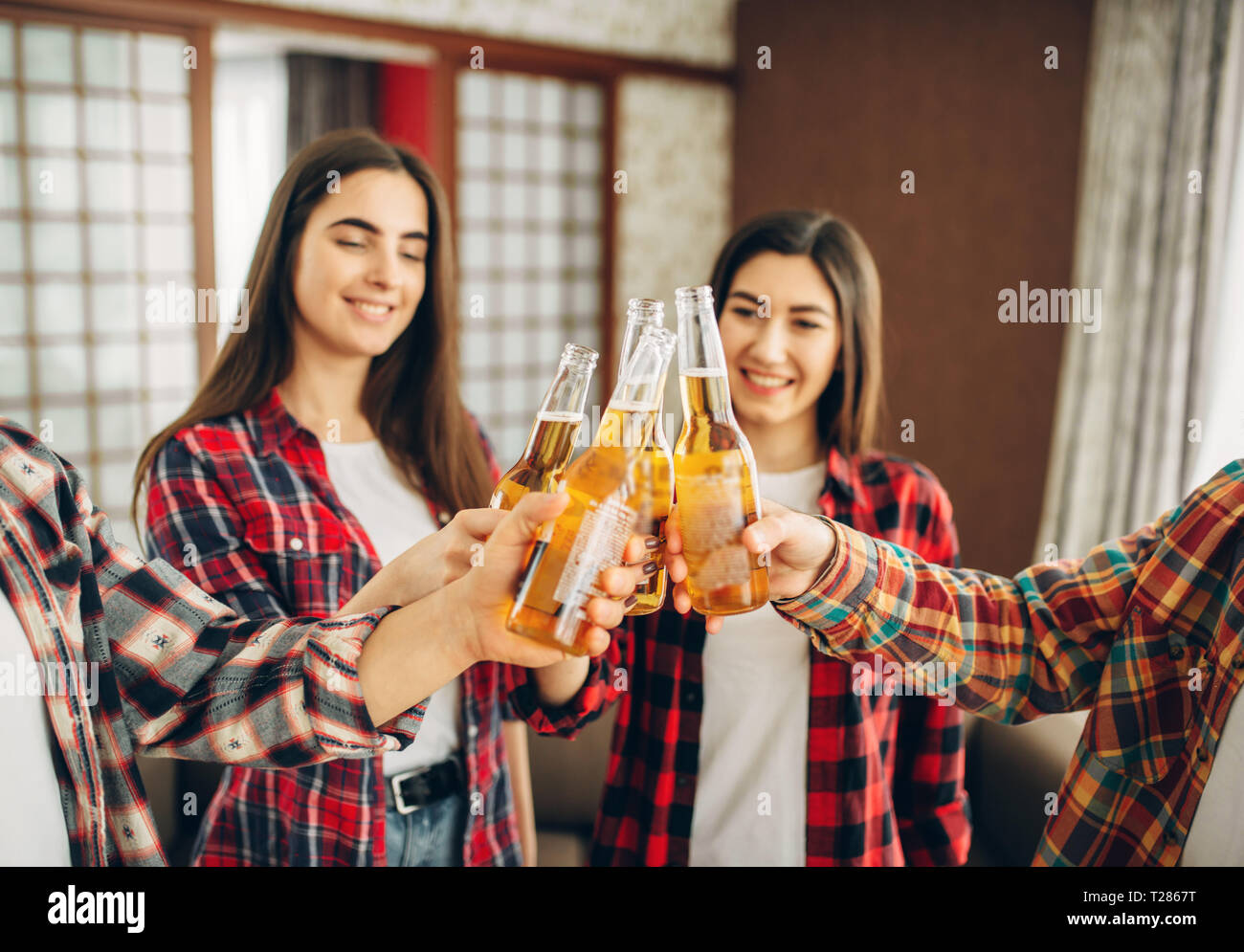 Smiling friends clink bottles with beer at the home party. Good ...