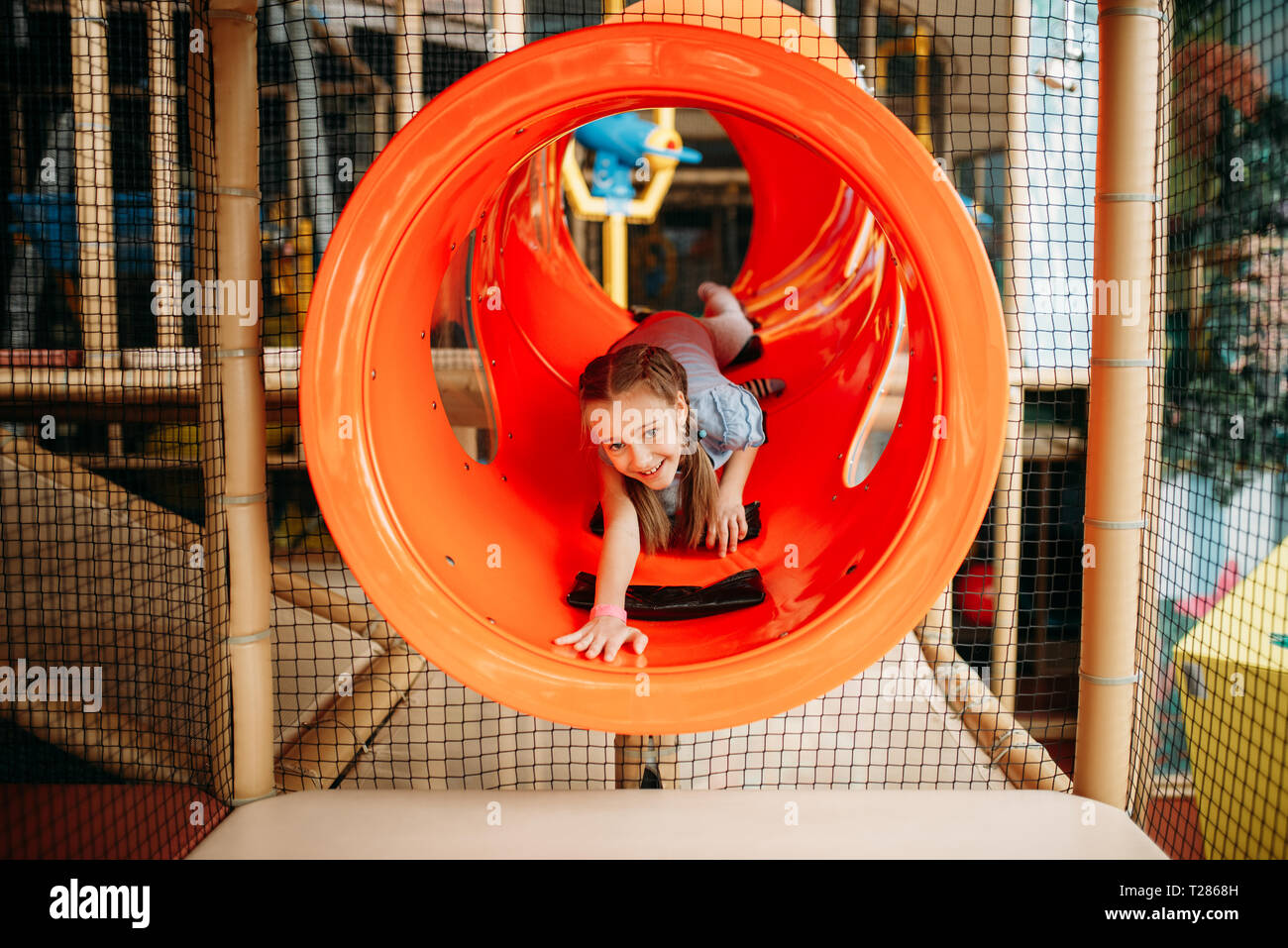 Funny girl climbing the maze in children game center. Excited child ...