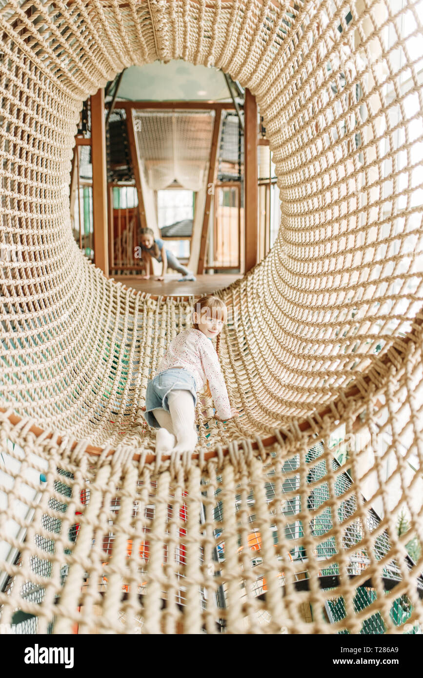 Funny girl plays in rope net, children game center. Excited child ...