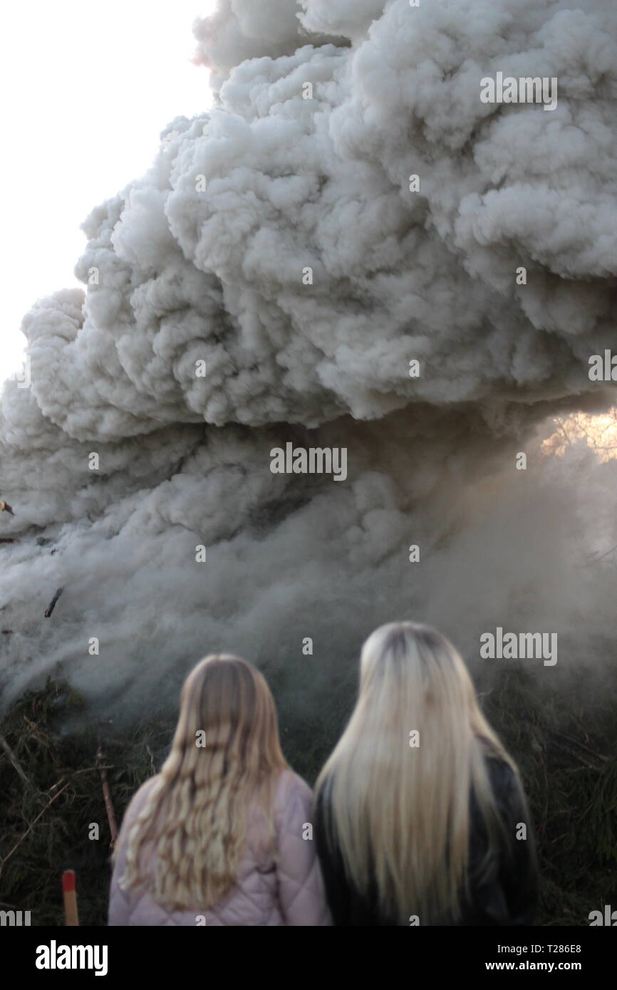 Two girls wathing a fire with heavy smoke. Celebrations of ...