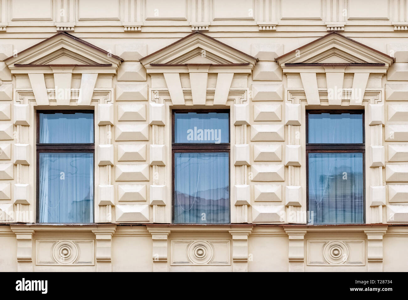 Three rectangular Windows with triangular cornices on a beige ...