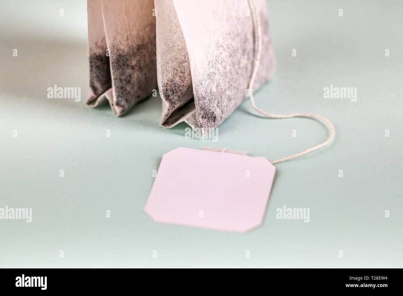 Two tea bags with white label isolated on light background, object ...