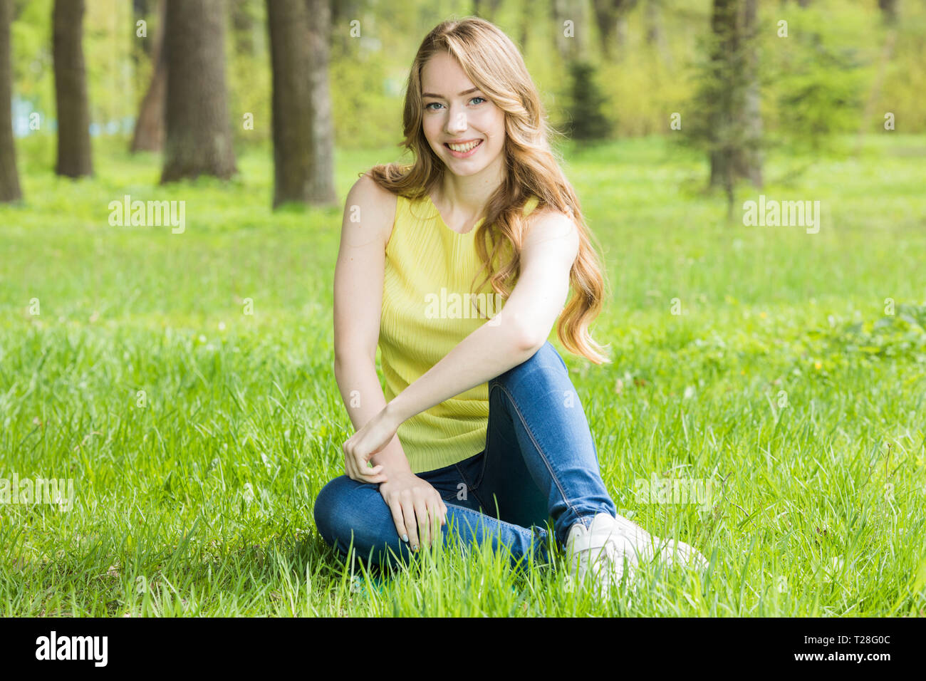 Pretty girl sitting on the grass in spring park and smiling Stock Photo ...