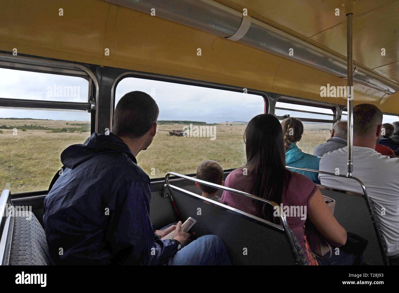 People in a vintage Routemaster bus looking at a burnt out military ...