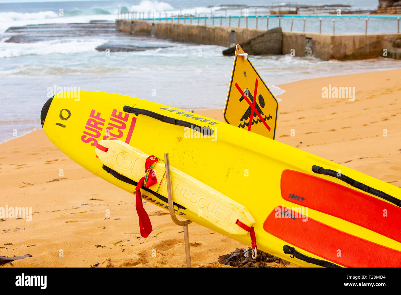 Lifeguards yellow surf rescue surfboard beside a beach no swimming sign ...
