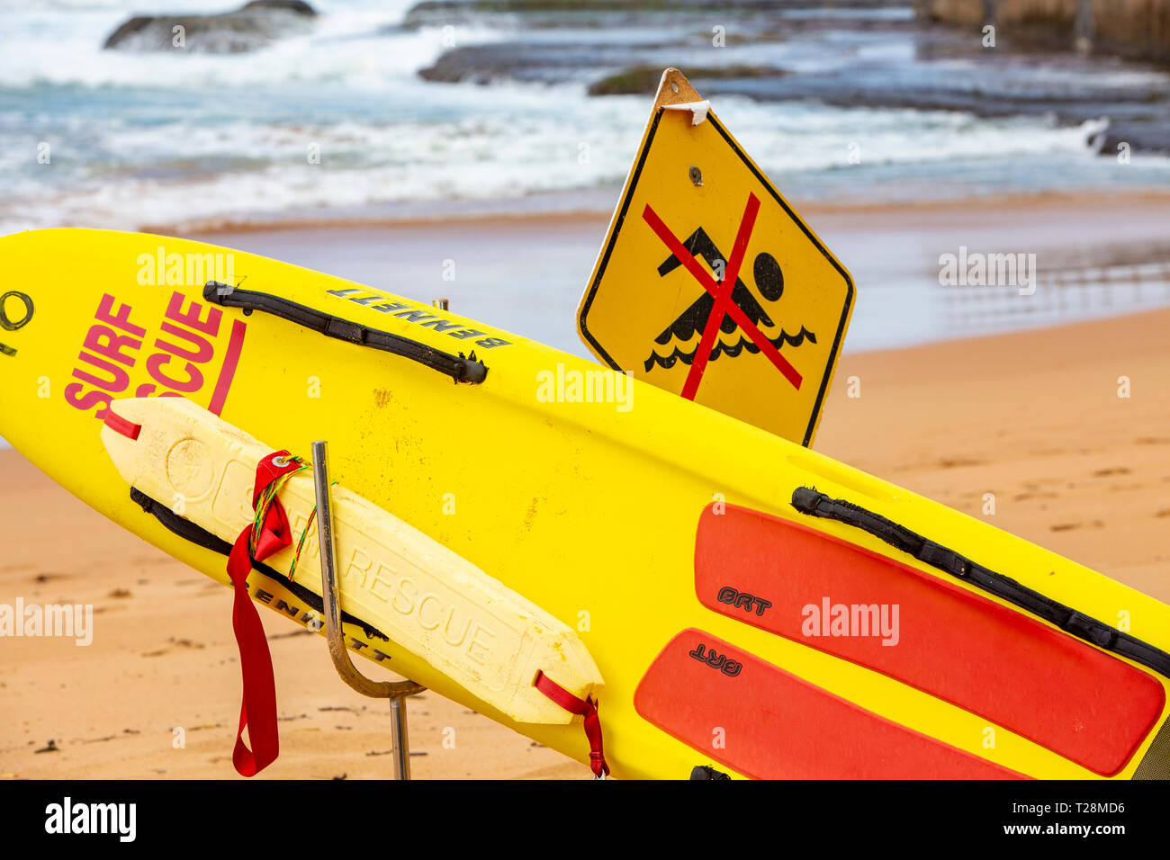 Lifeguards yellow surf rescue surfboard beside a beach no swimming sign ...
