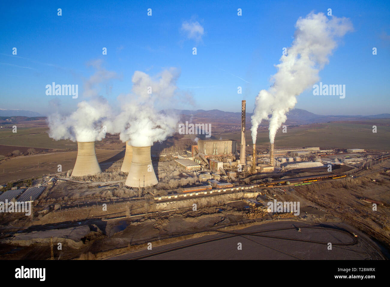 Aerial shot of coal-fired power plant and its cooling tower with steam ...