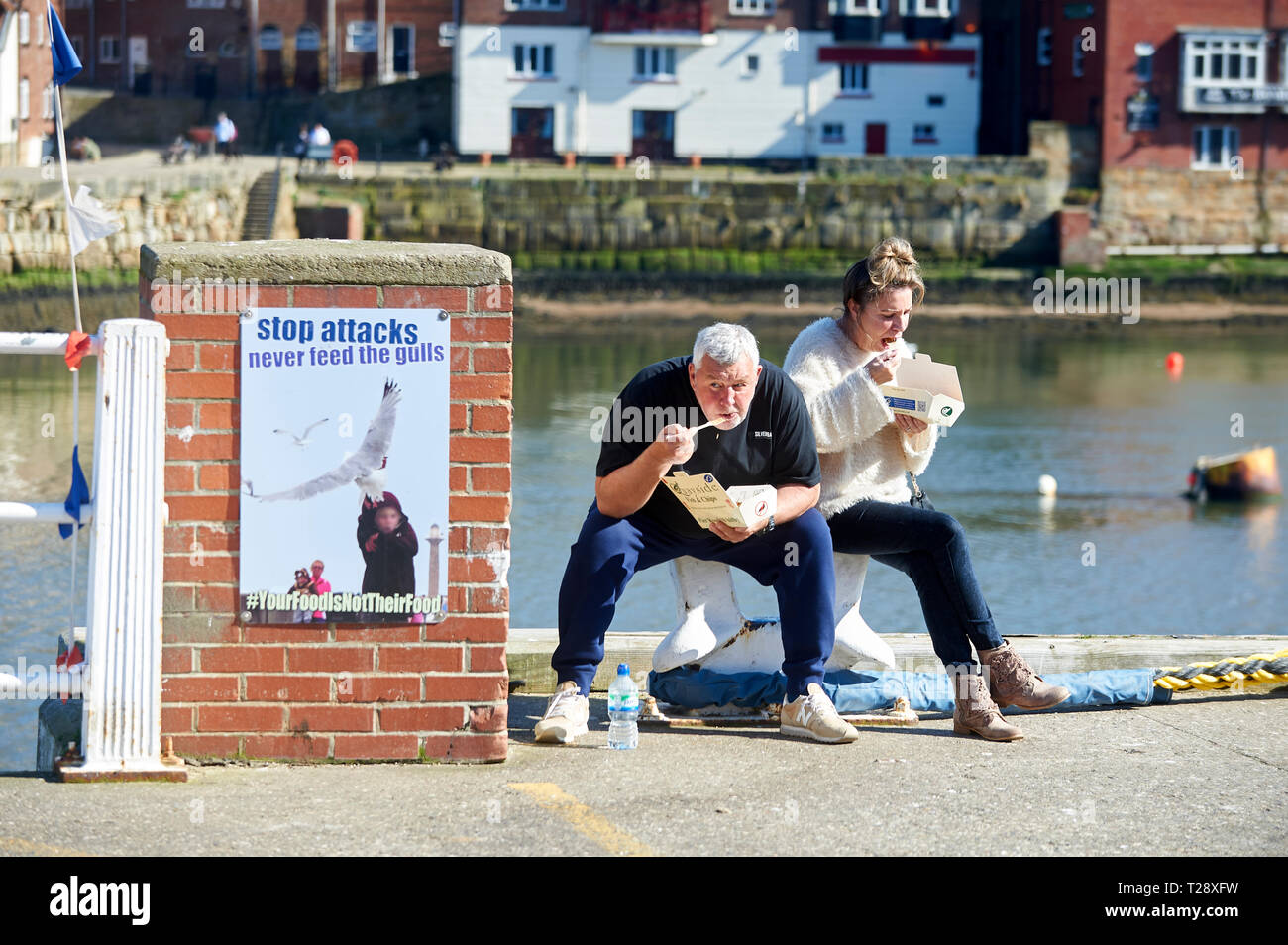 Couple eating Fish & Chips sitting on the harbour at Whitby , North ...