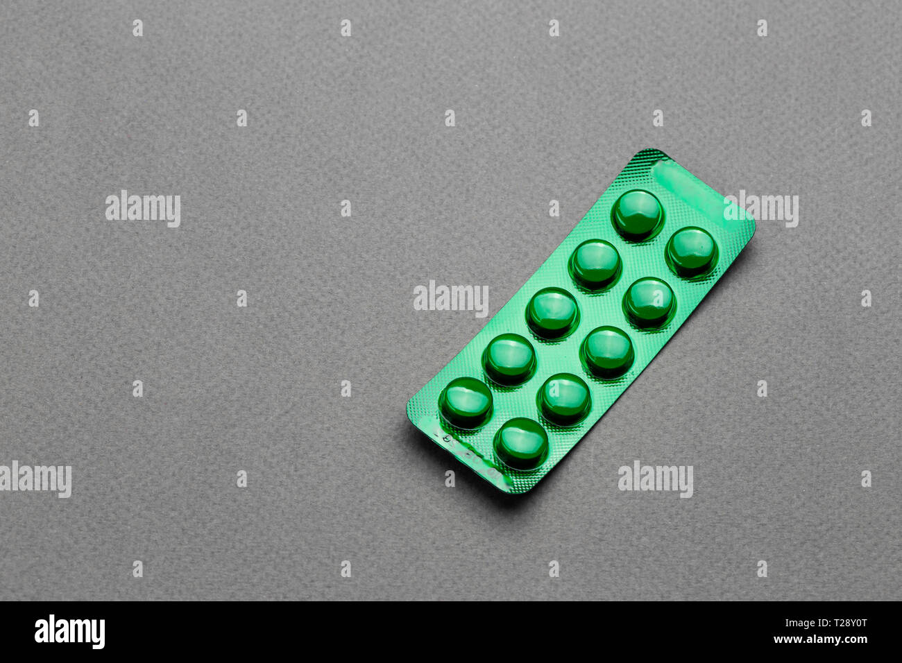 pills in a green blister on a black background. drug treatment of ...