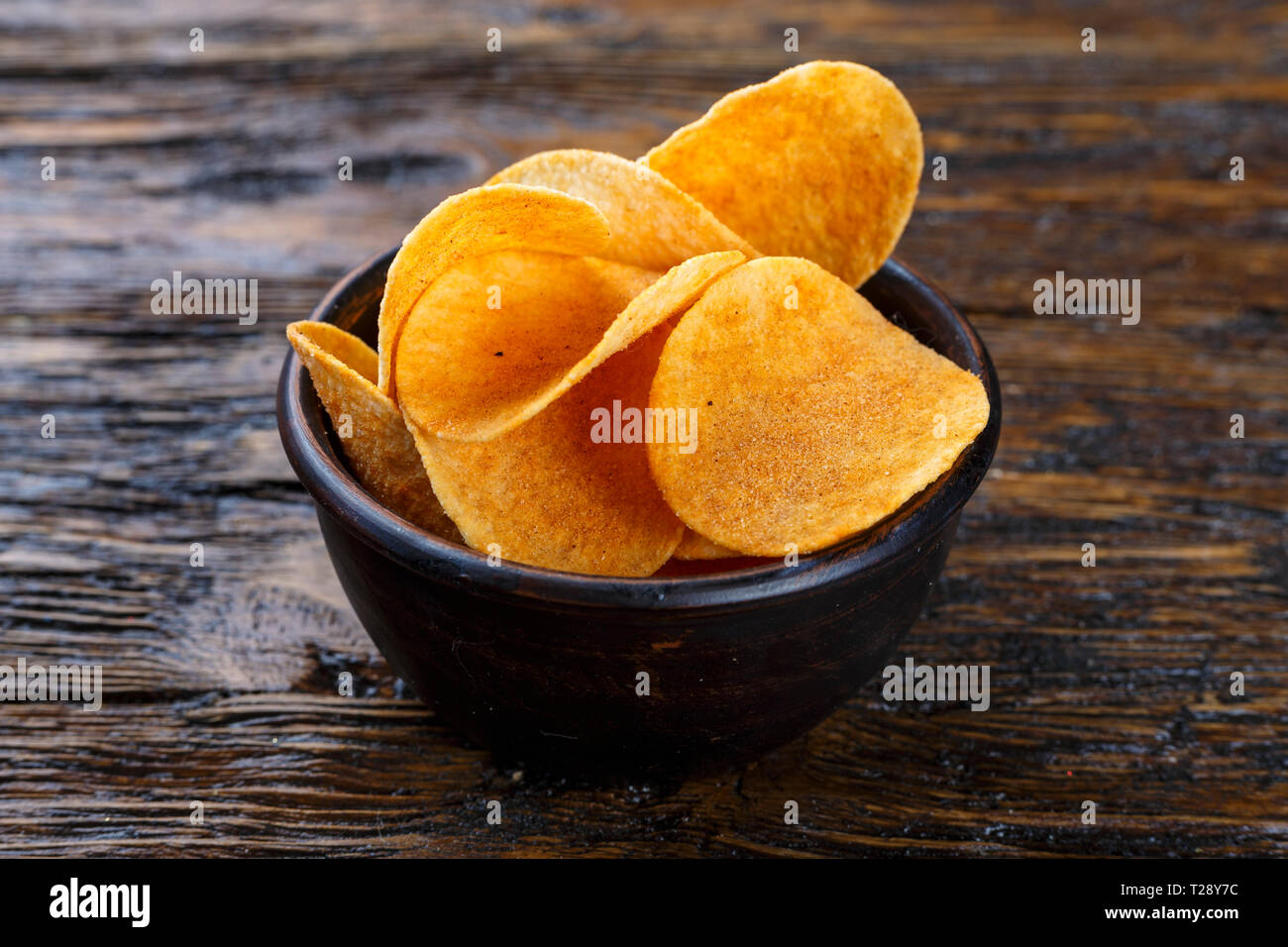 Crispy potato chips in a clay plate on old kitchen table Stock Photo ...