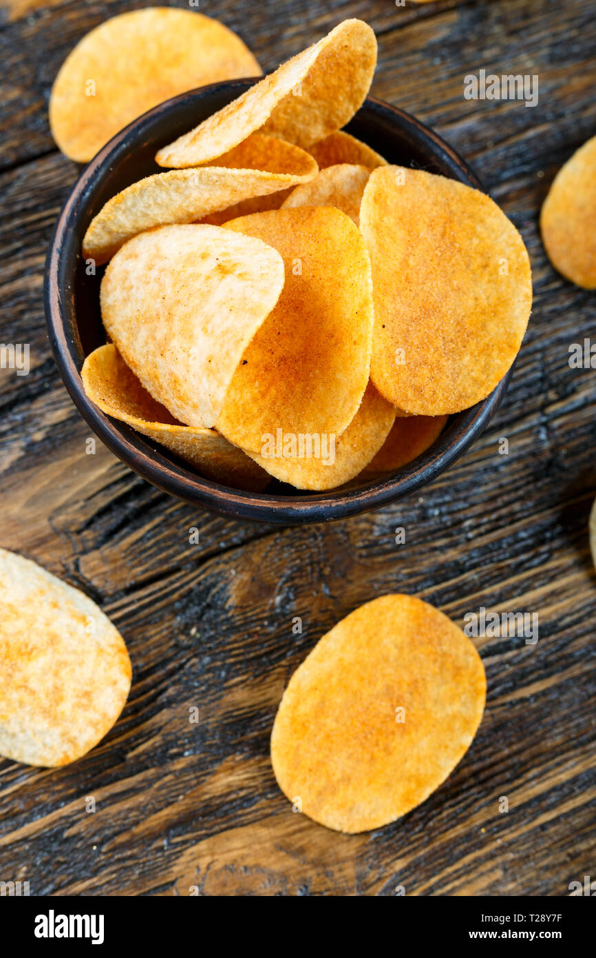 Crispy potato chips in a clay plate on old kitchen table Stock Photo ...