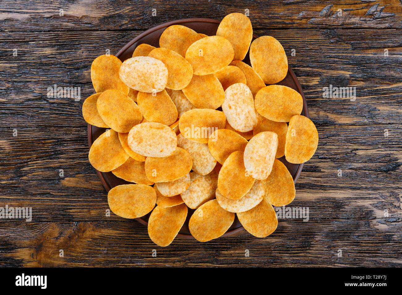 Crispy potato chips in a clay plate on old kitchen table Stock Photo ...