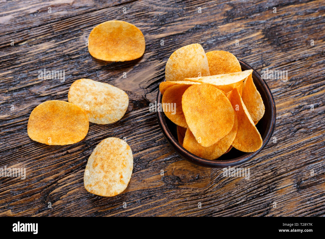 Crispy potato chips in a clay plate on old kitchen table Stock Photo ...
