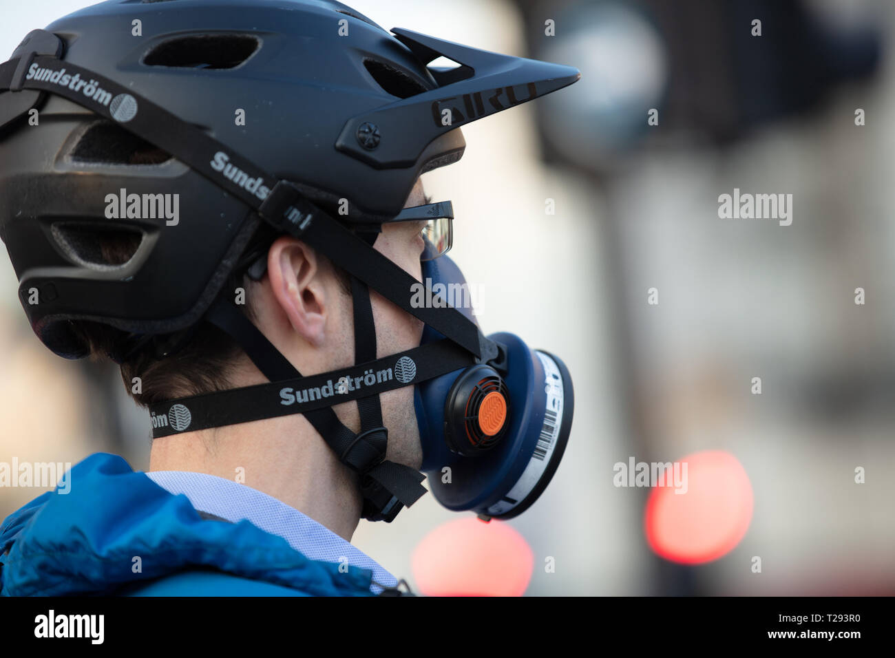 Cyclist in London, UK, wears a safety helmet and a mask with a filter ...