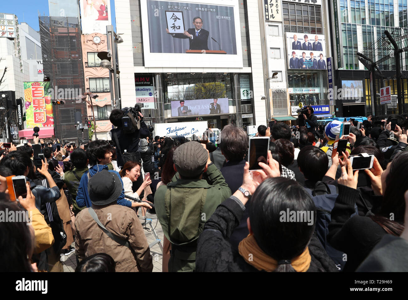 Tokyo, Japan. 1st Apr, 2019. People watch a large screen showing Chief ...
