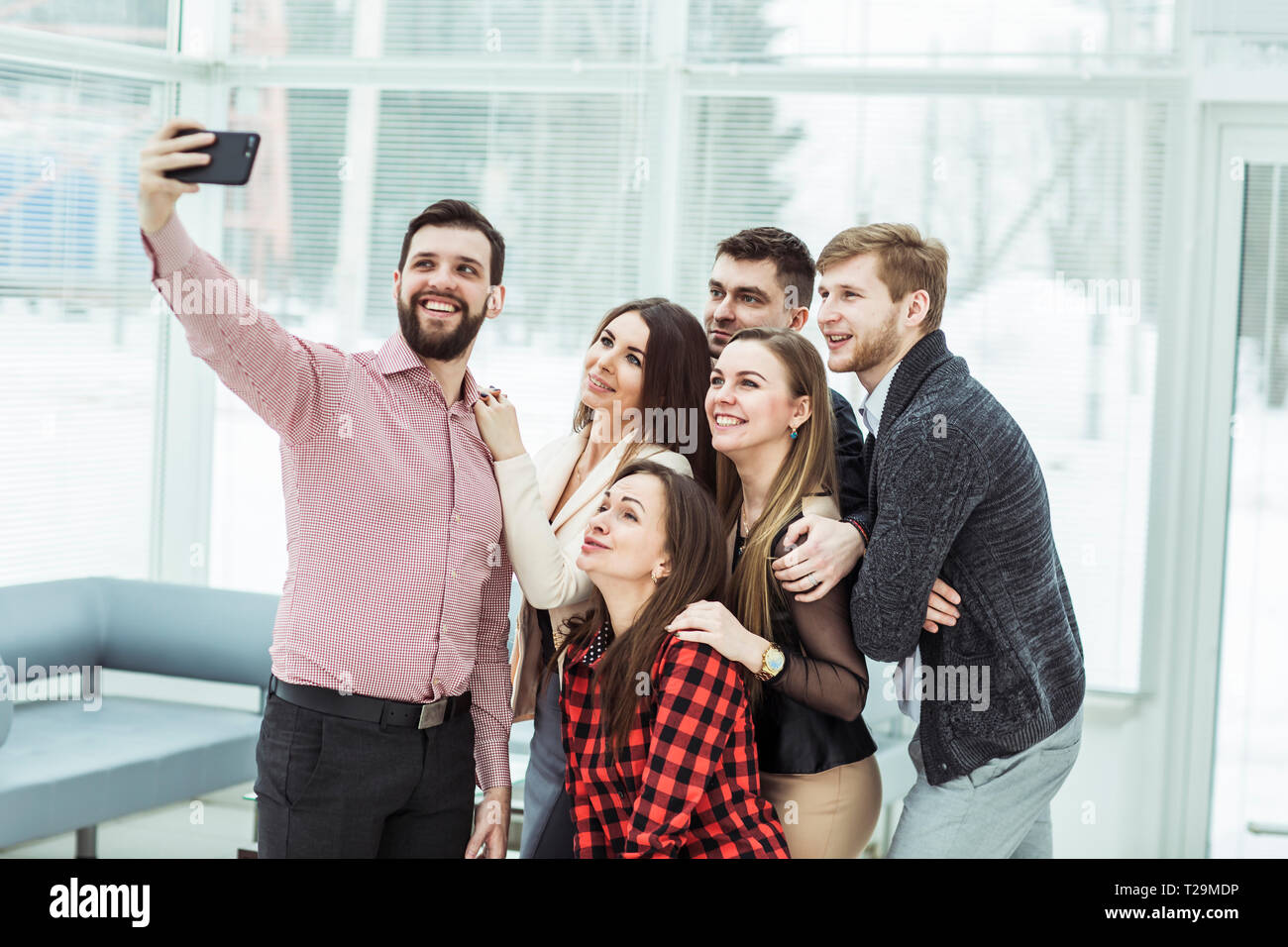 friendly business team taking a selfie while standing near window in ...