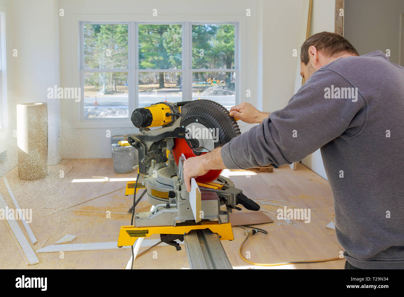 Carpenter at work using circular saw cutting wood moldings baseboard ...