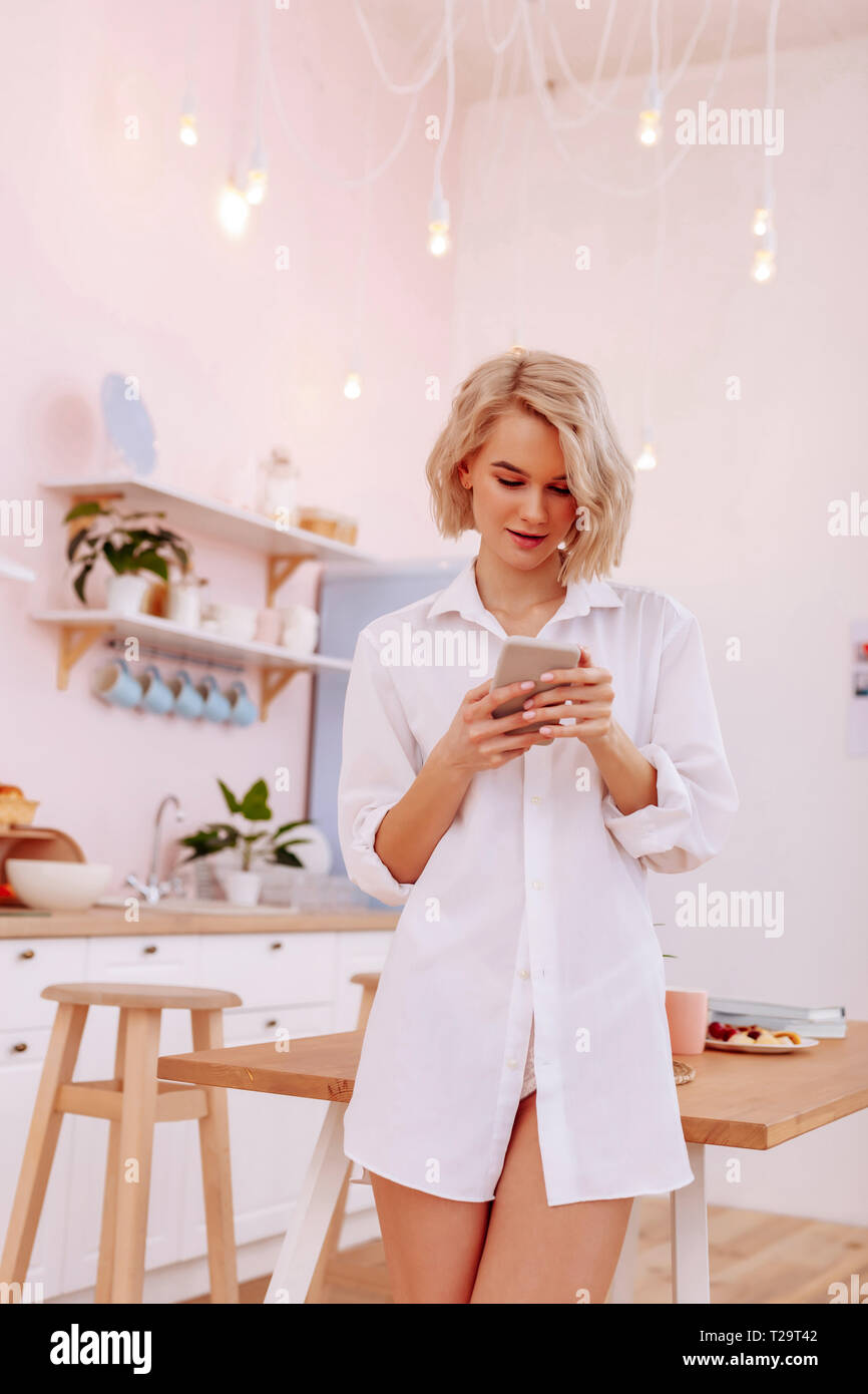 Young woman wearing white shirt standing in the kitchen Stock Photo - Alamy