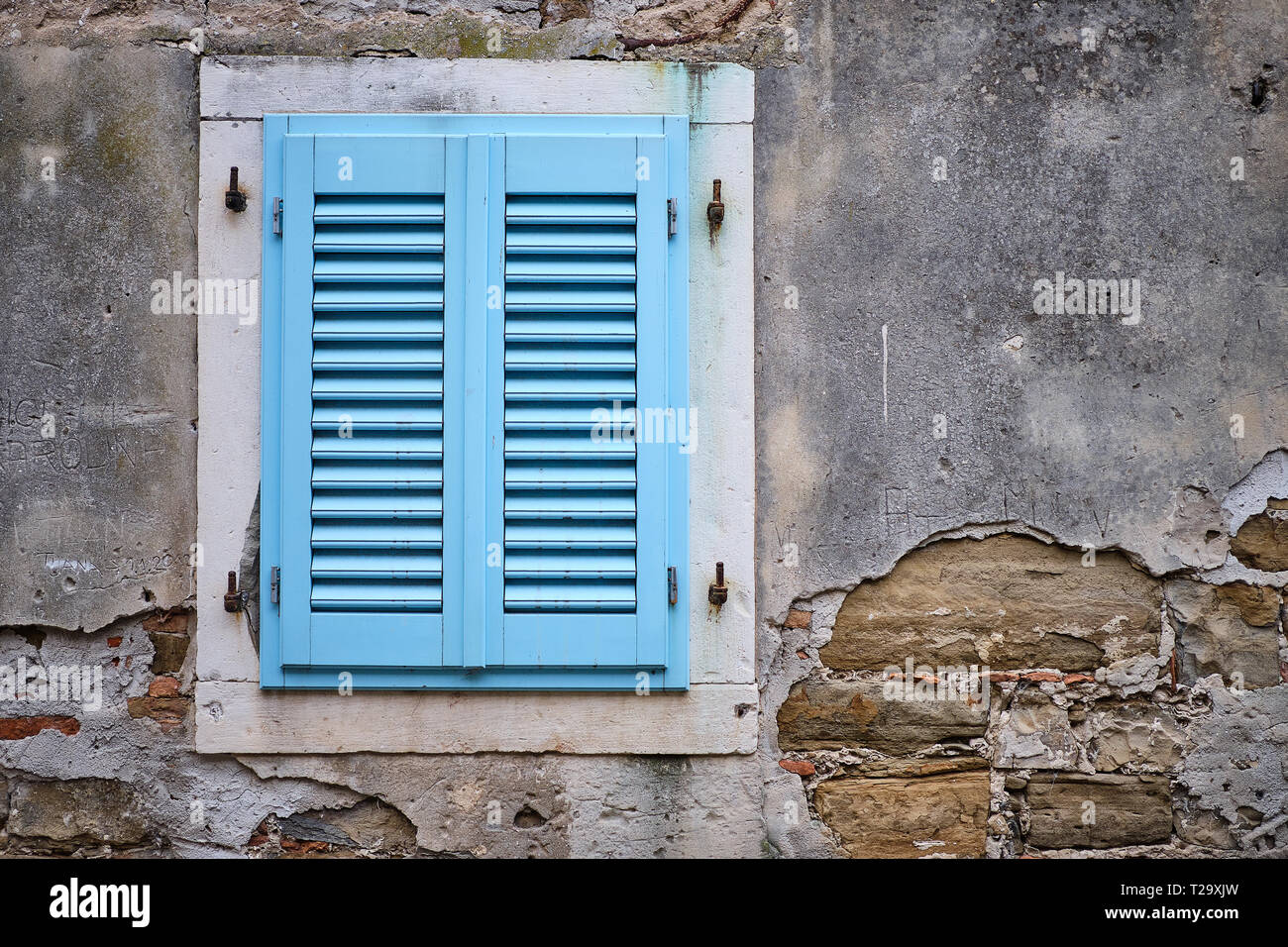 window with closed blue shutters. Texture concrete walls, crumbling and ...