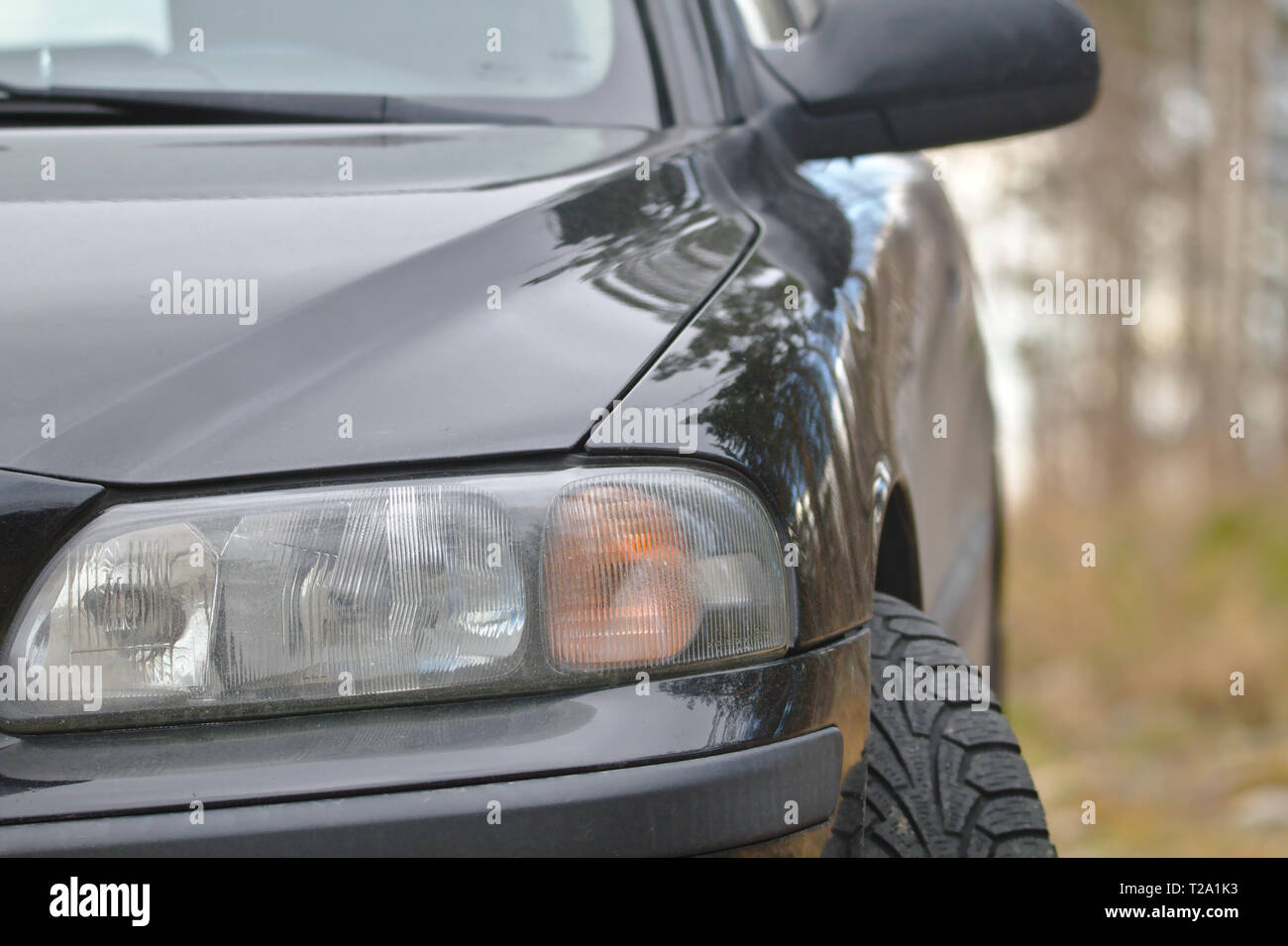 One headlight, sideview mirror and part of front of a black passenger ...