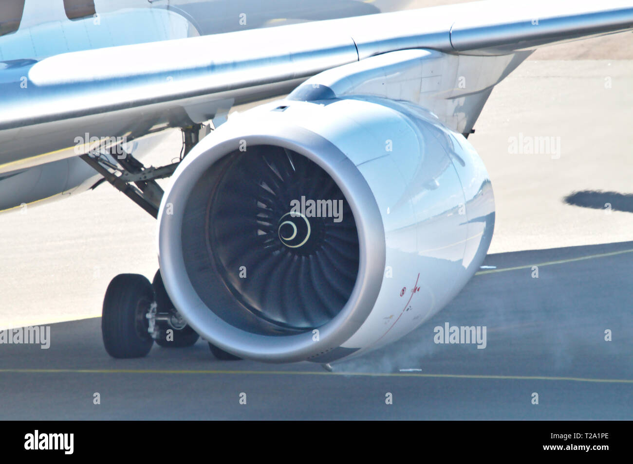 Closeup of left wing and smoking jet engine of a white commercial ...