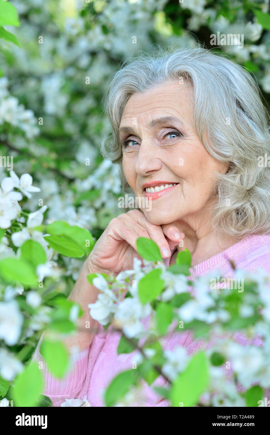 Portrait of beautiful senior woman posing near blooming tree Stock ...