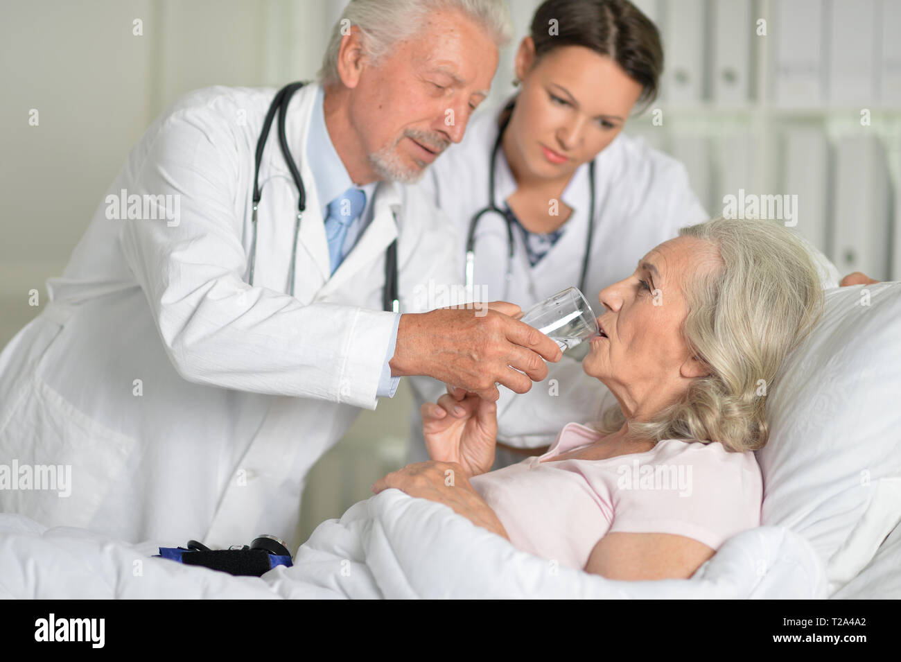 Two professional doctors inspecting patient at ward Stock Photo - Alamy